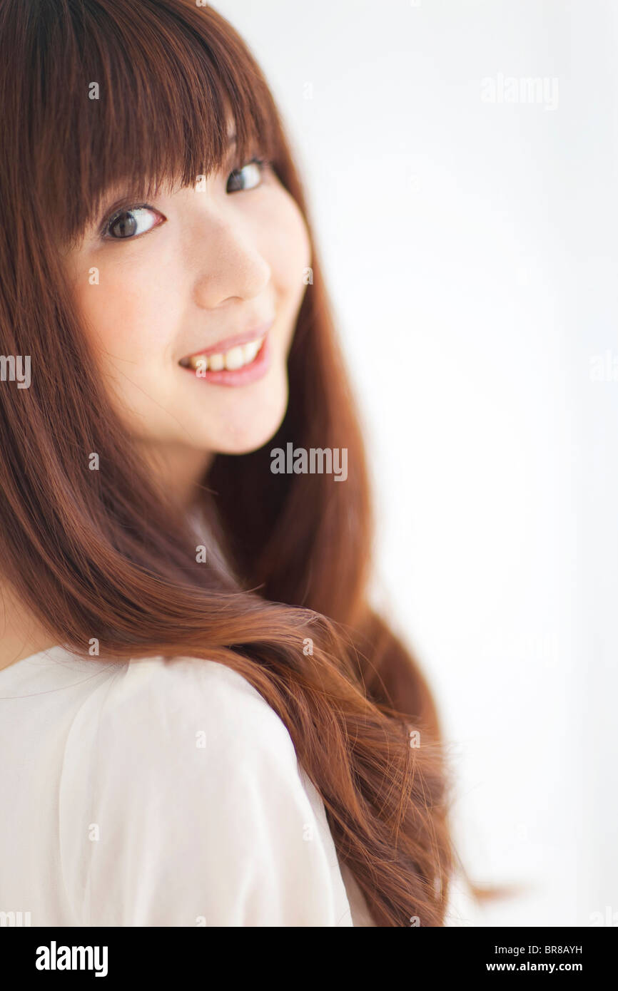 Portrait of young woman, smiling and looking back, white background ...