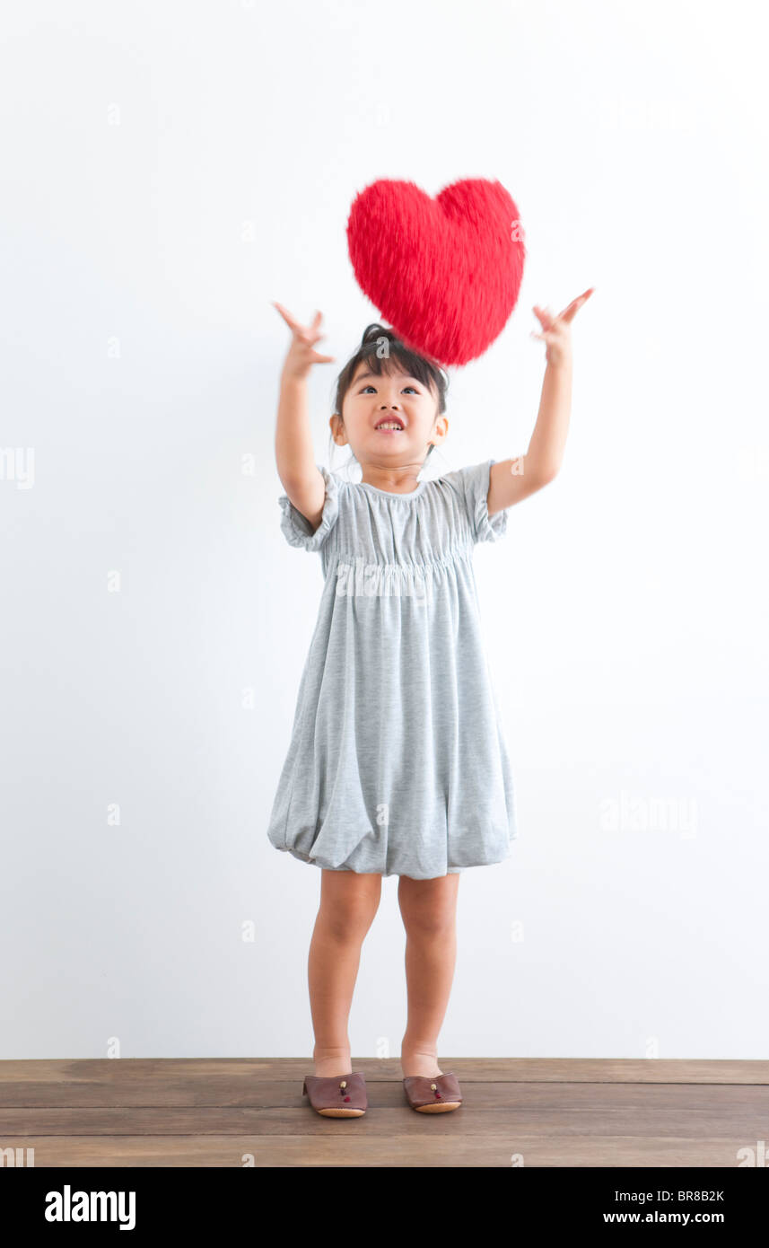 Girl throwing up red heart cushion, white background Stock Photo - Alamy