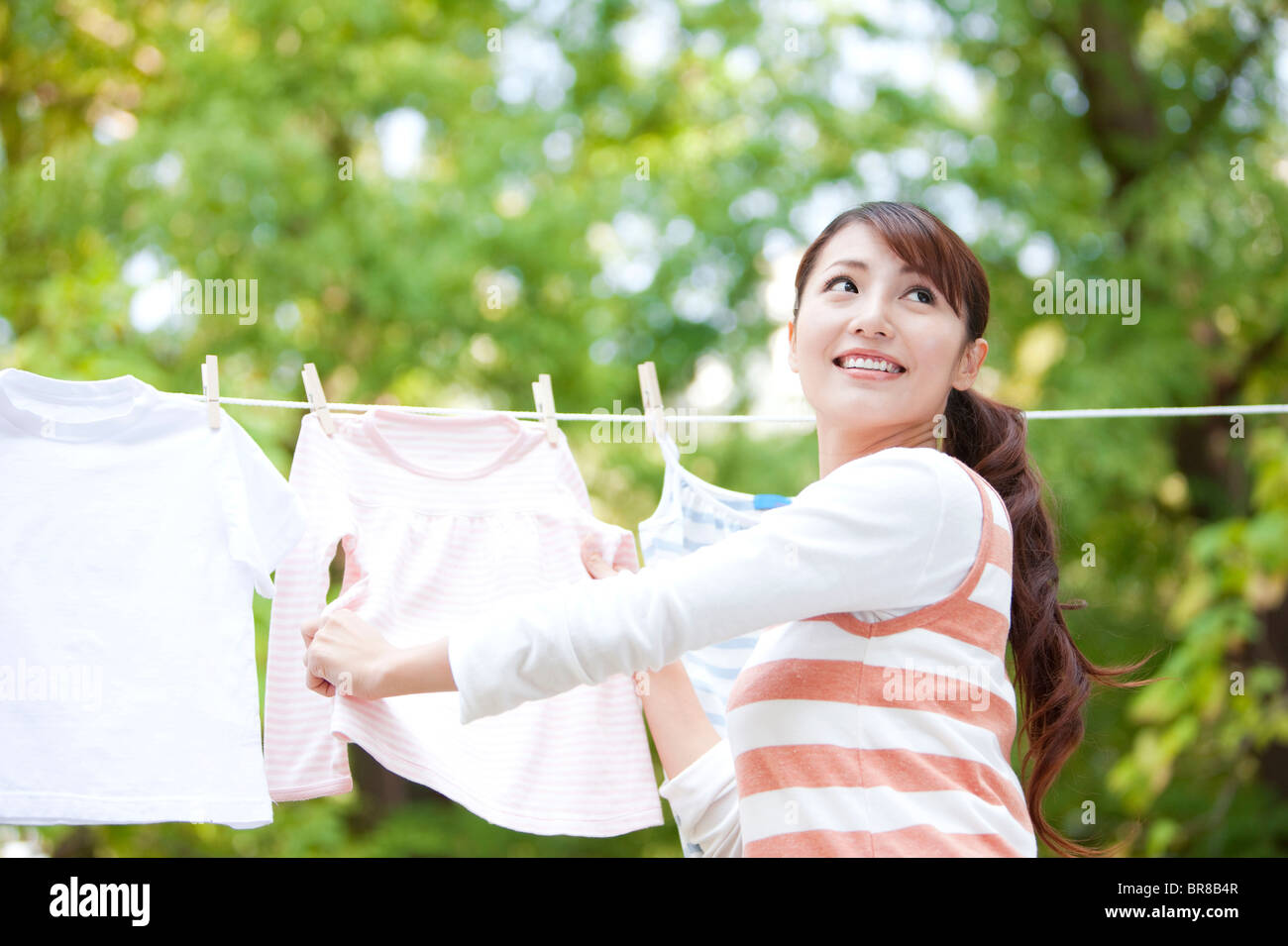 Woman drying laundry, smiling and looking back Stock Photo - Alamy