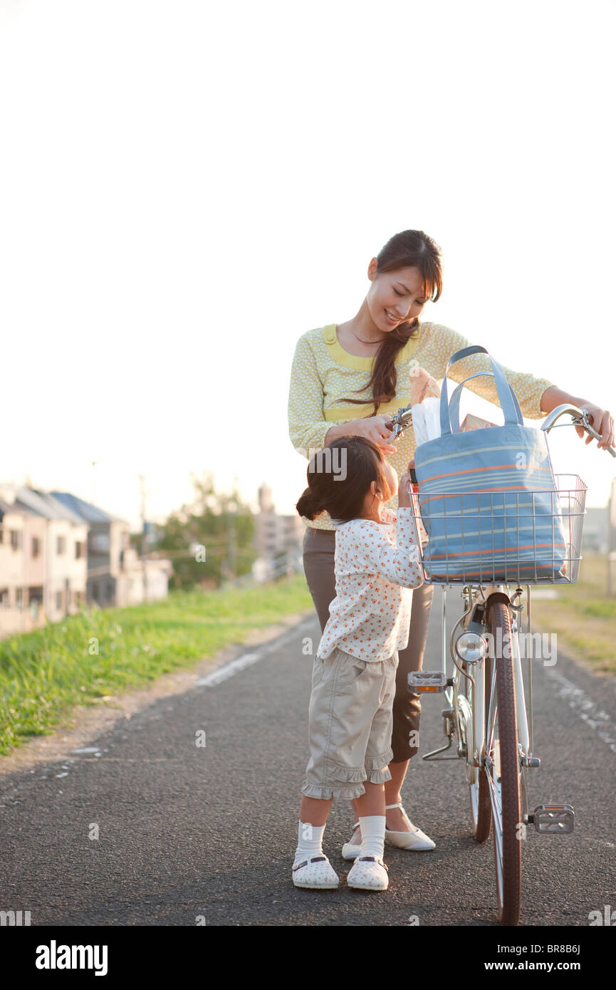 Girl with mother walking at riverbank, mother pushing bicycle Stock ...