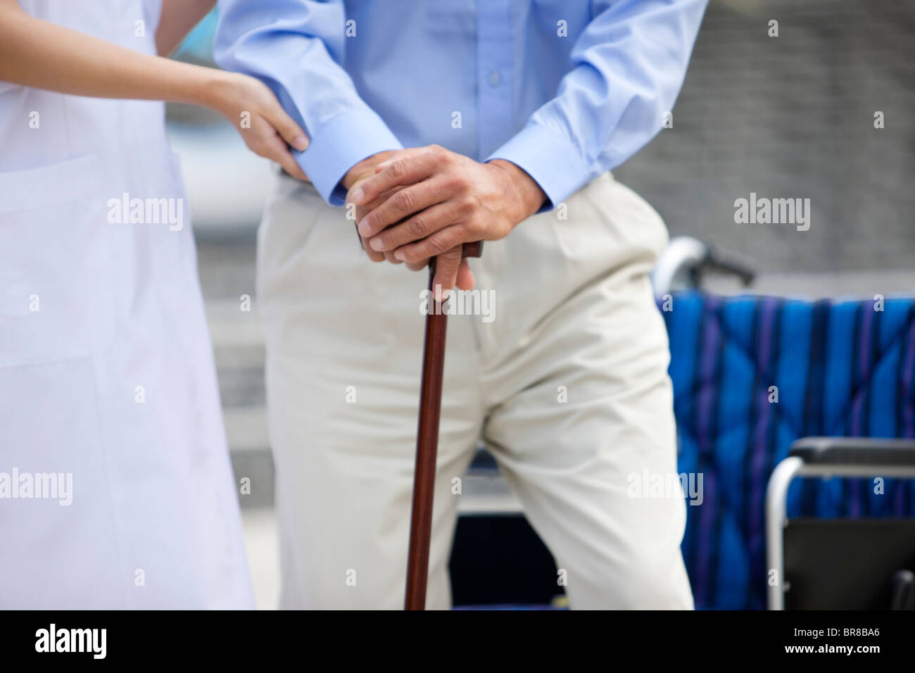 Nurse assisting man with cane Stock Photo - Alamy