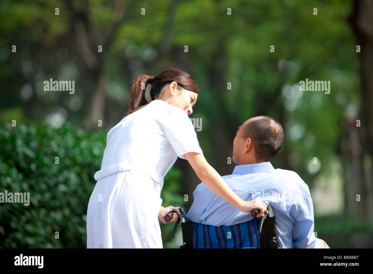 Nurse pushing man on wheelchair Stock Photo - Alamy