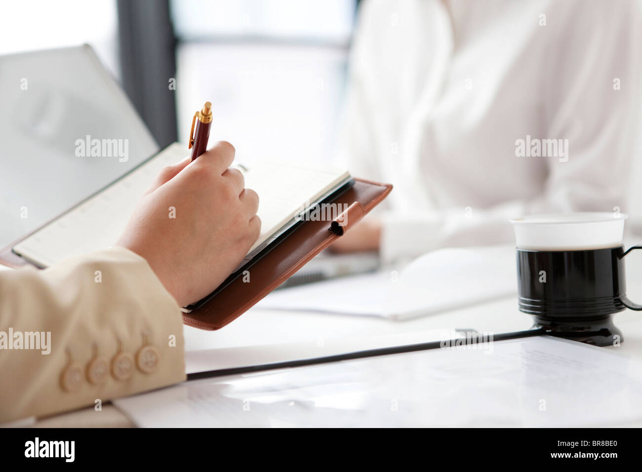 Businesswoman writing in her diary Stock Photo - Alamy