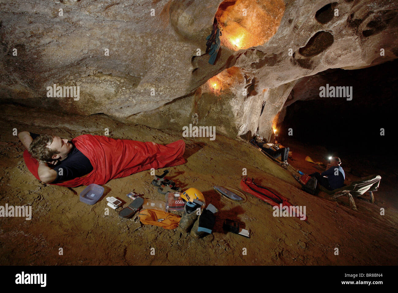 A cave explorer relaxing in his sleeping bag before having to get up ...