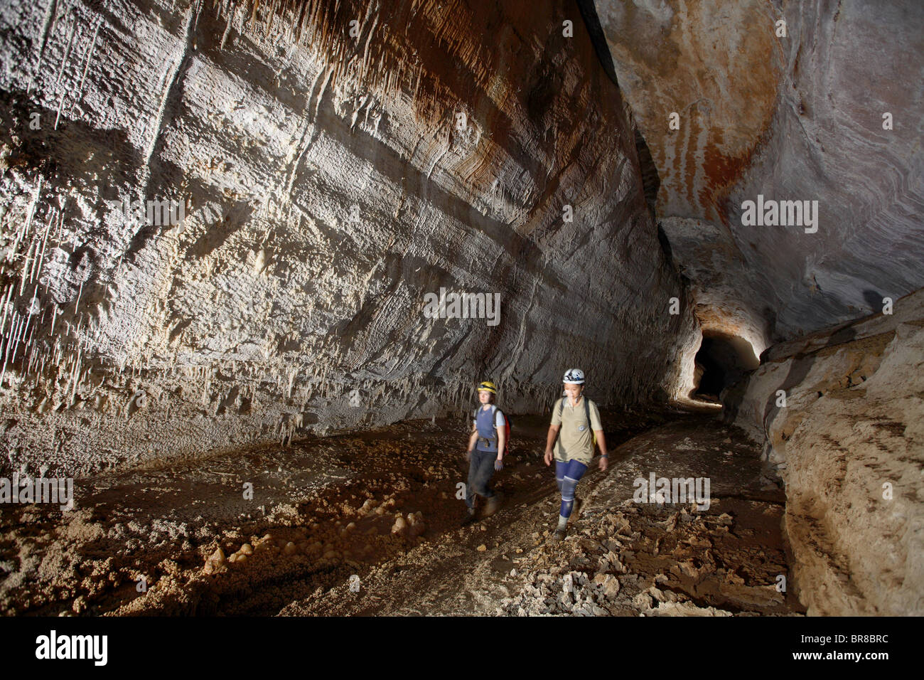 Two female cave explorers walk easily through a satisfying tunnel ...
