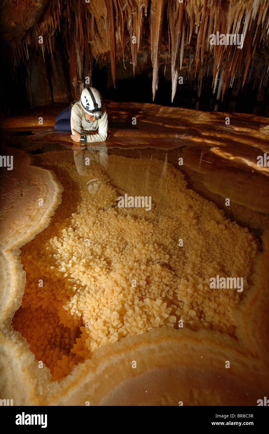 A female cave explorer looks into a very pretty Gour Pool. The floor of ...