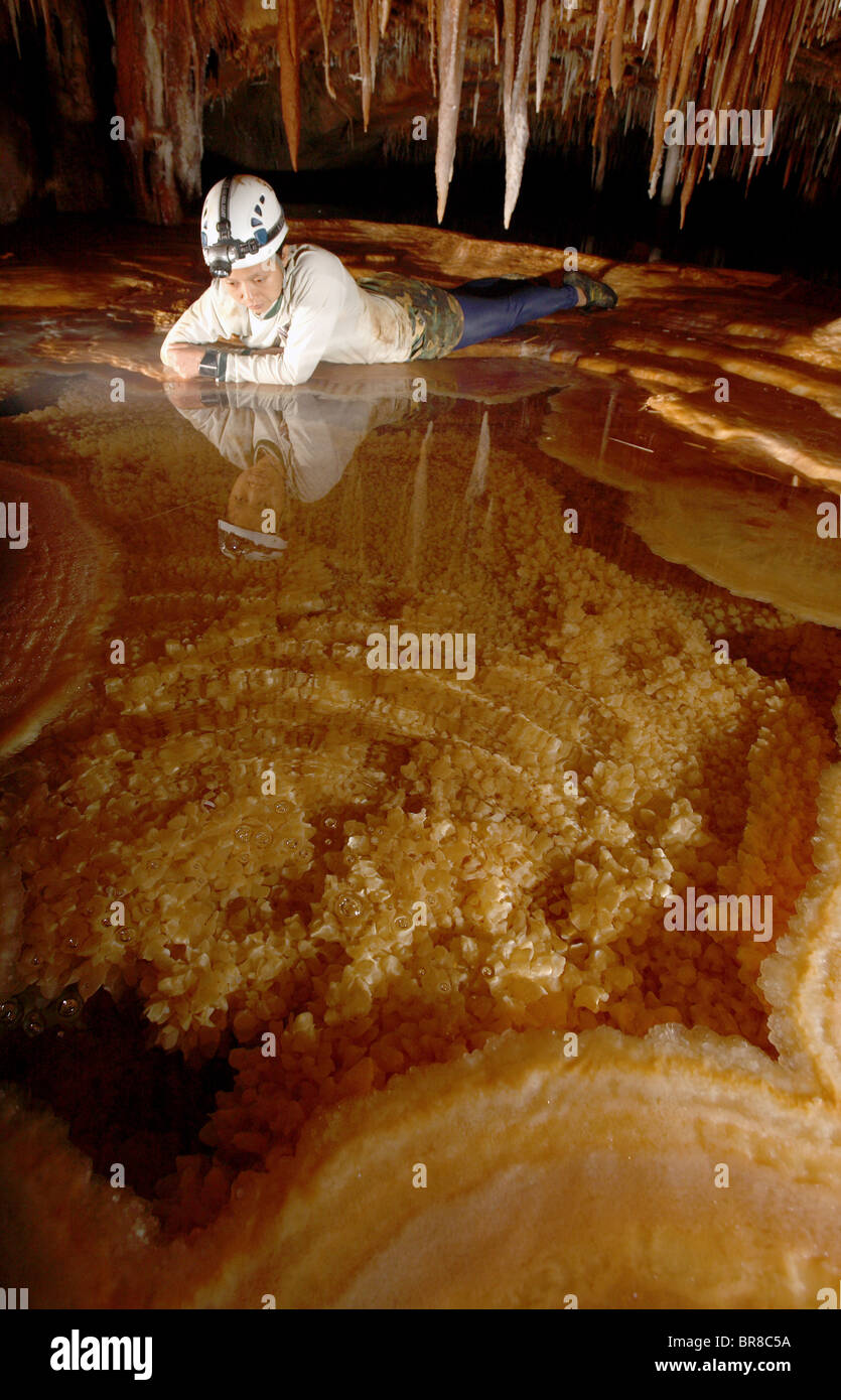 A female cave explorer looks into a very pretty Gour Pool. The floor of ...