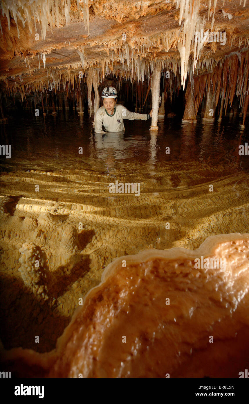 A female cave explorer wades through the terminal Gour Pool so very ...