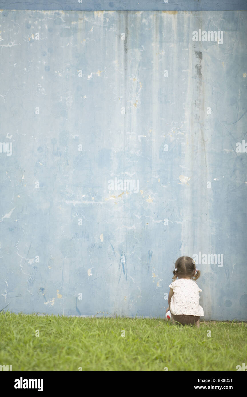 Girl crouching facing a wall, rear view Stock Photo - Alamy