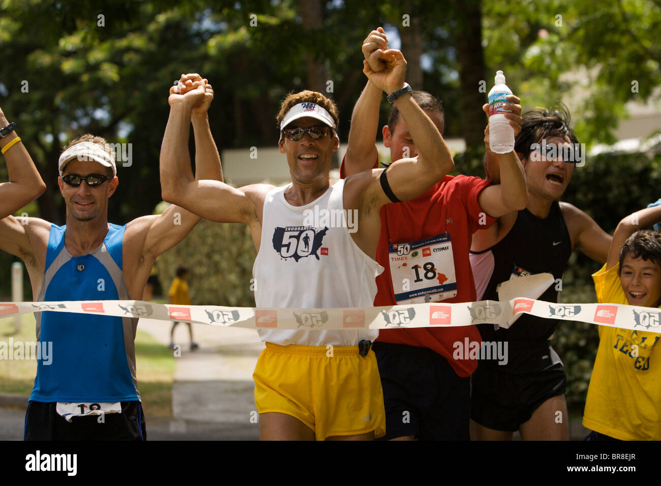Runners holding hands while crossing the finish line of a marathon in ...