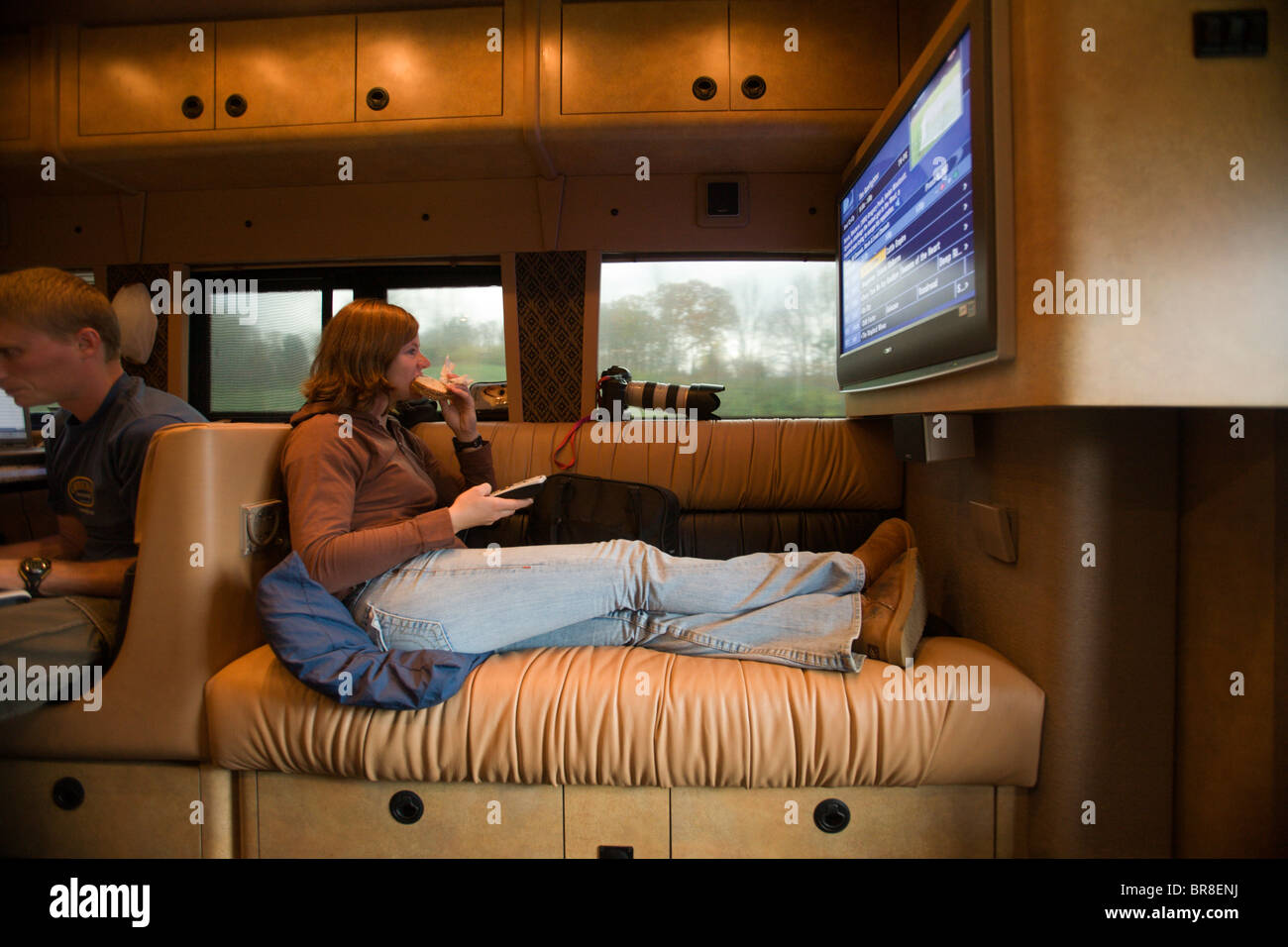 Woman eating and watching TV in a tour bus in Bristol New Hampshire ...