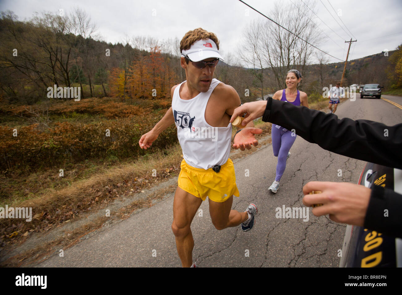Runner grabbing a snack from support crew during a marathon in Stowe ...