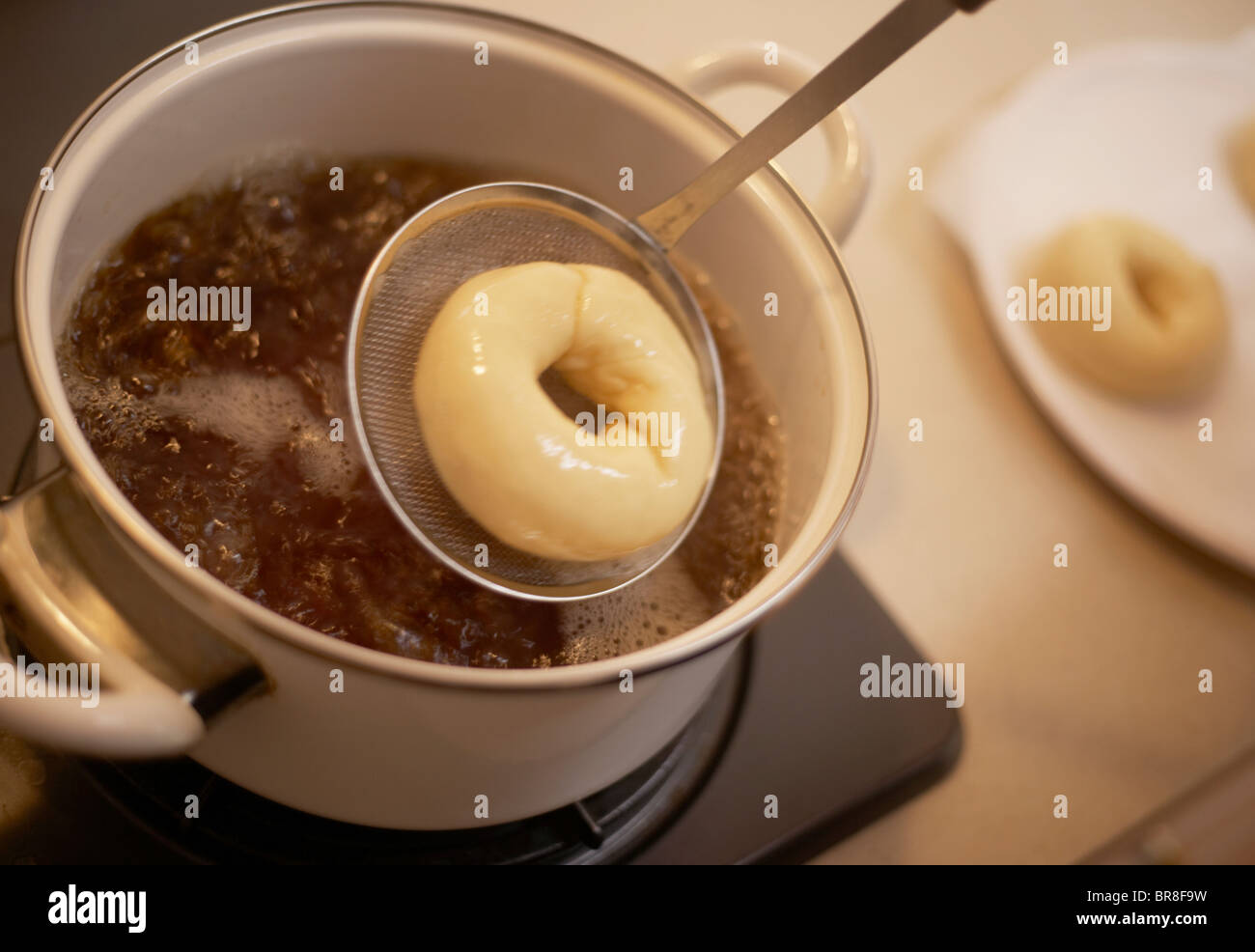 Bagel dough being boiled in pan, close up Stock Photo - Alamy