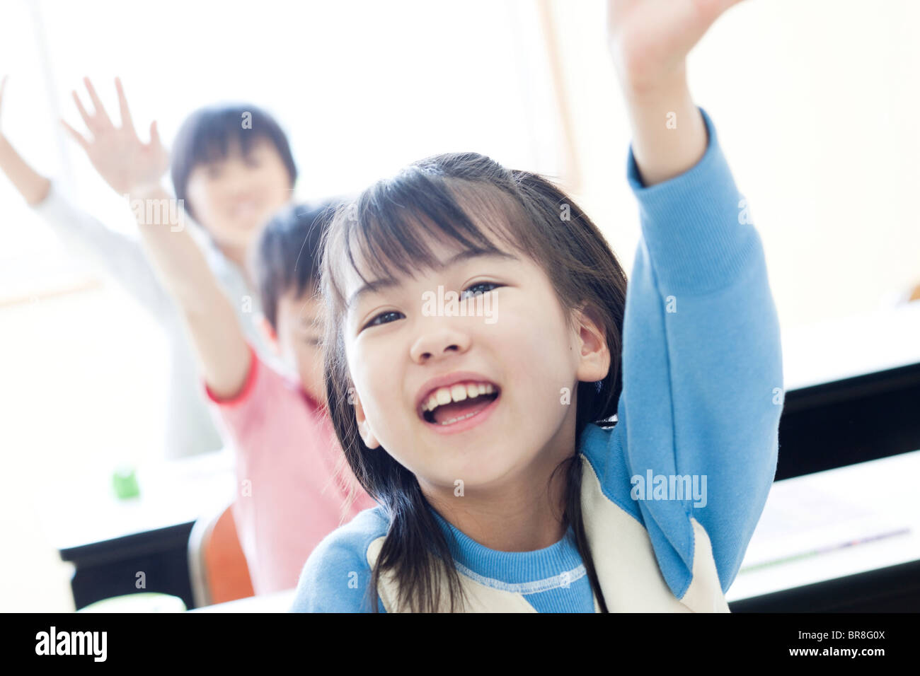 Children with their hand raised at cram school Stock Photo - Alamy