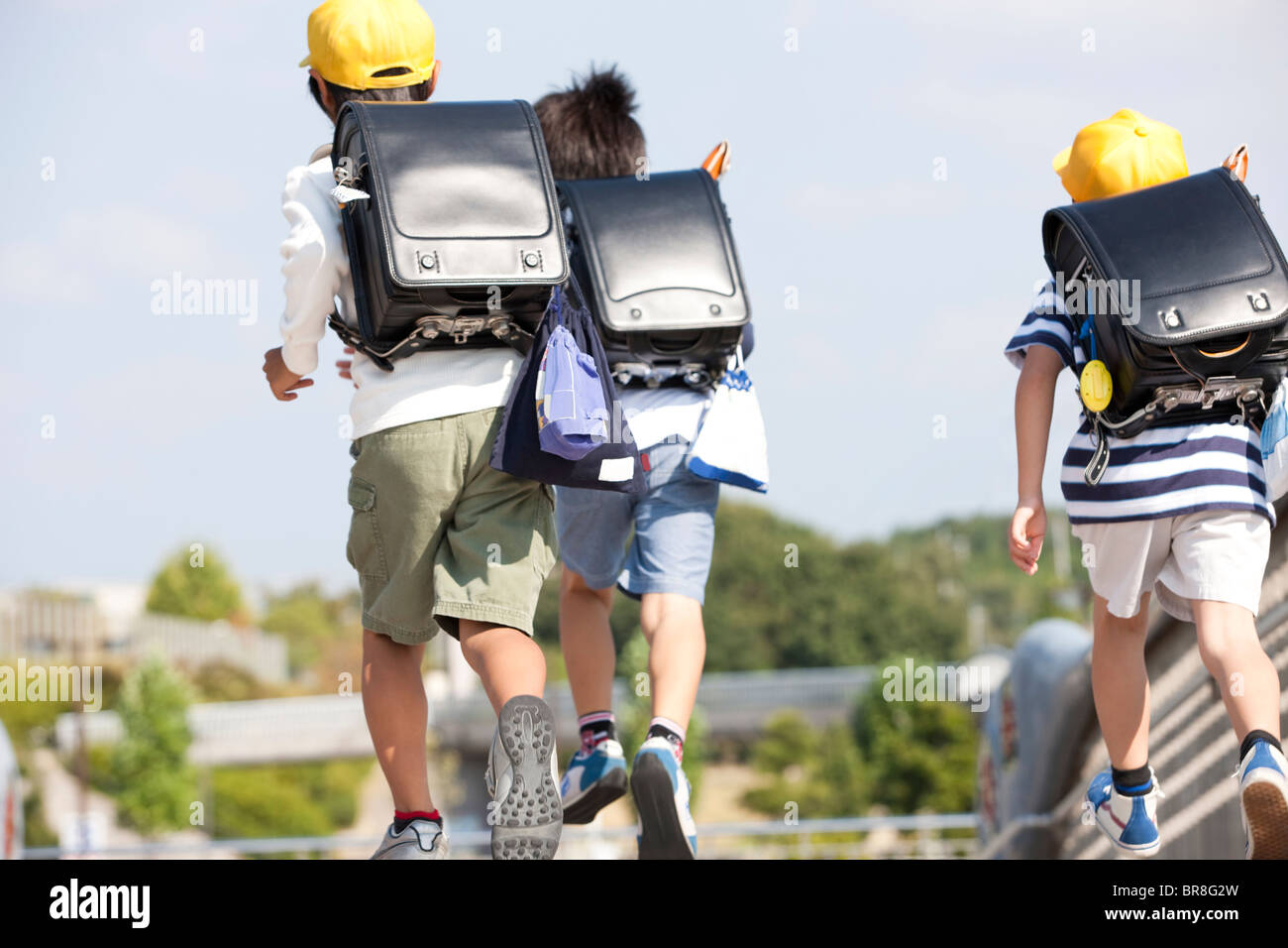 Elementary school students running to school, rear view Stock Photo - Alamy