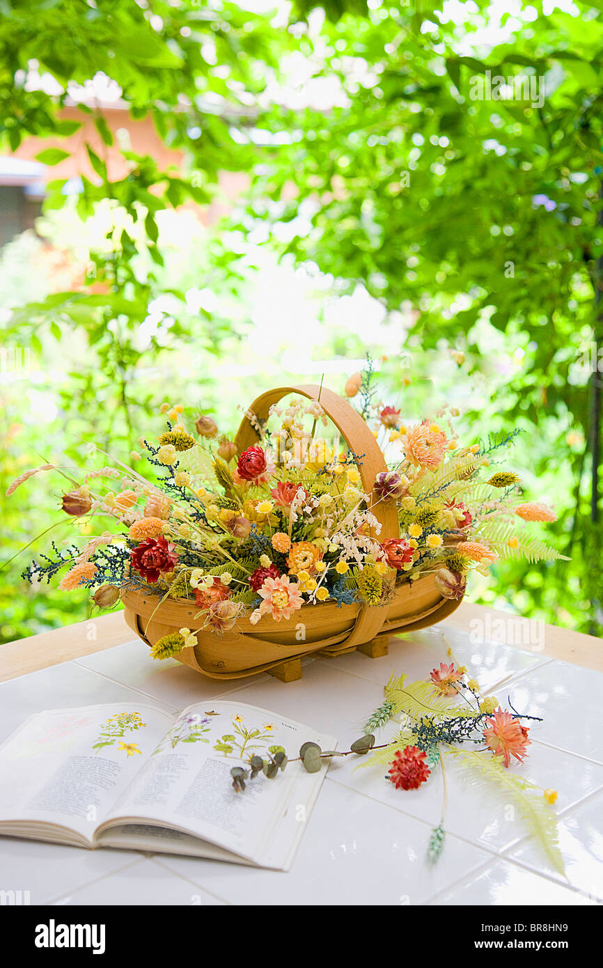 Book and basket of flowers on table Stock Photo - Alamy