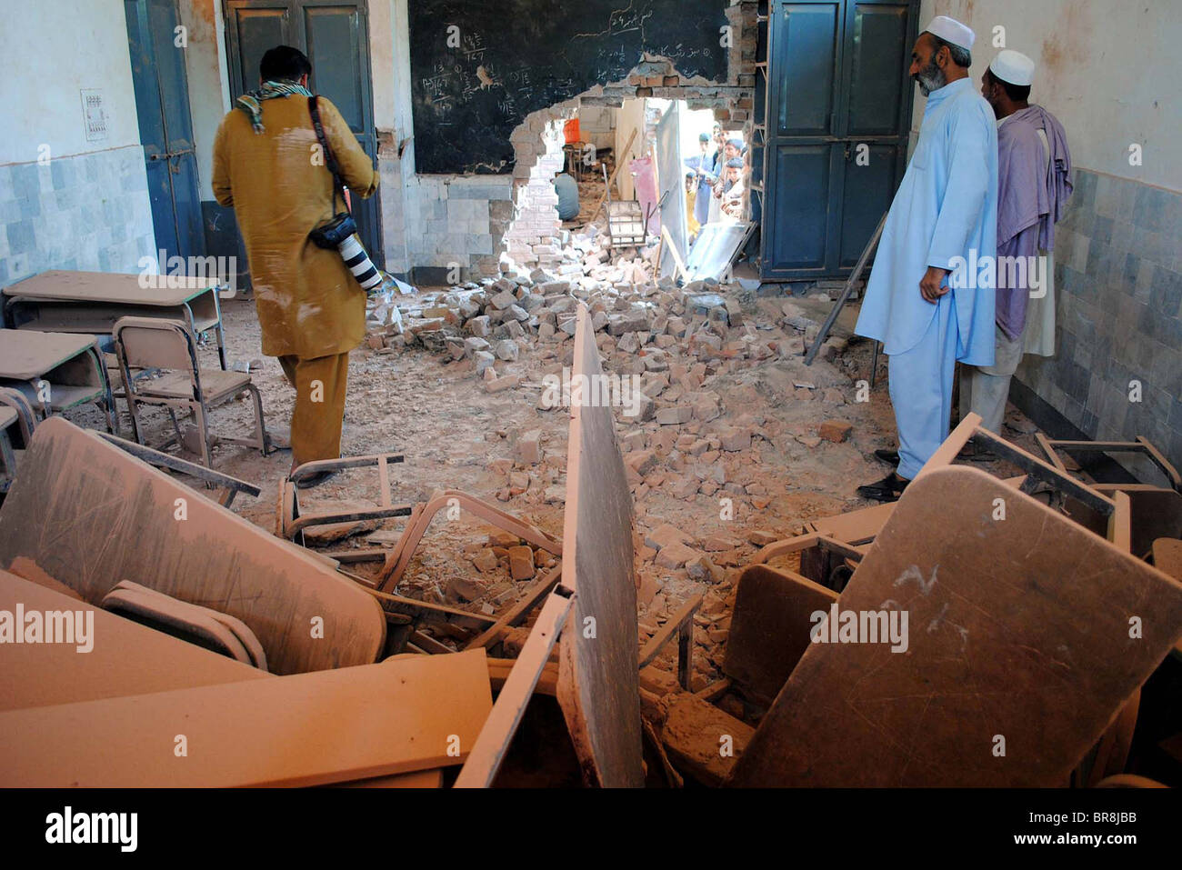 People look damaged wall of a classroom, which was destroyed in bomb ...