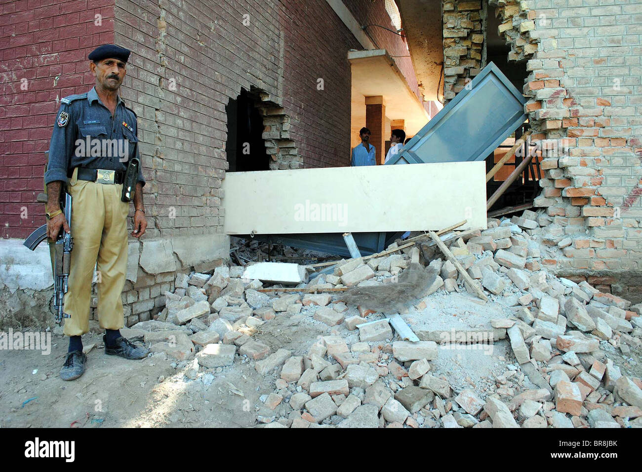 Police official stands guard at debris of classrooms, which were ...