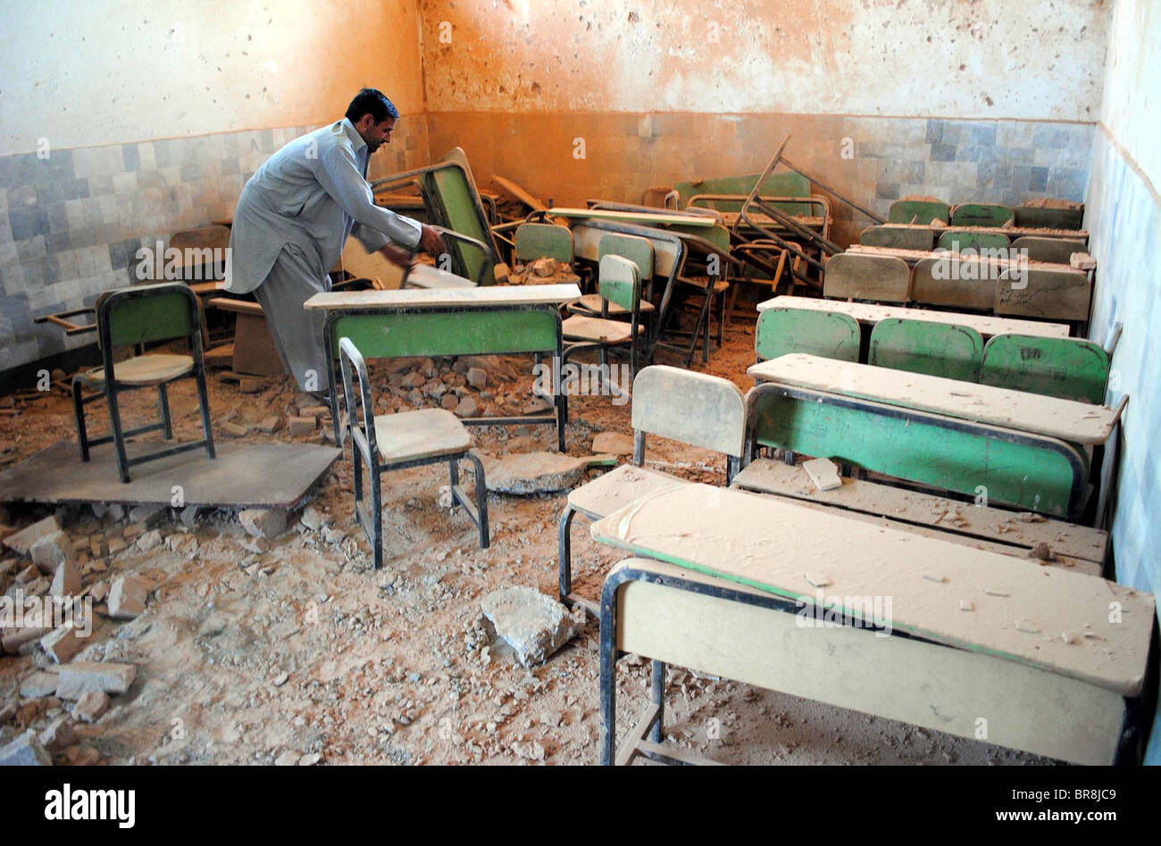 Man looks damaged desks of a classroom, which was destroyed in bomb ...