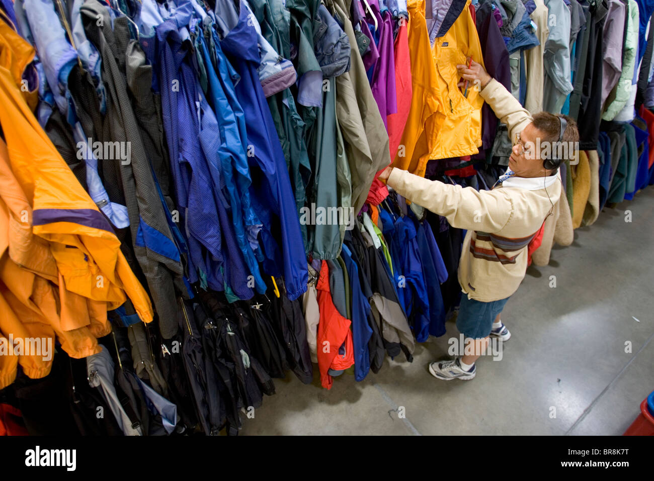A man sorts through clothes on a rack in a clothing distribution center ...