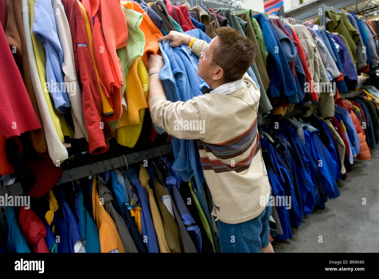A man sorts through clothes on a rack in a clothing distribution center ...
