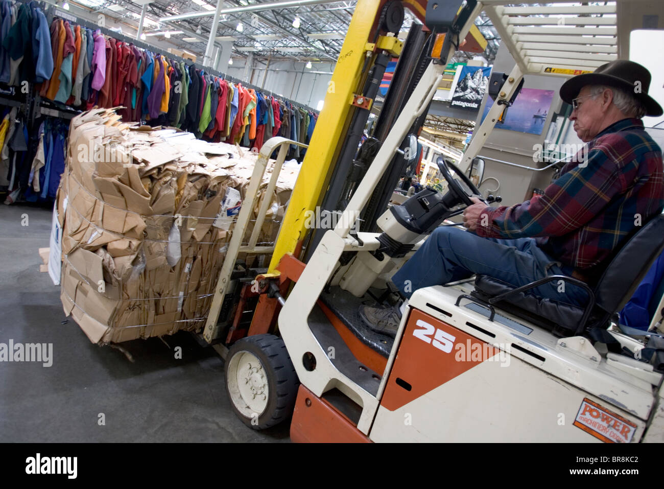 A man moving recycling boxes with a forklift in a clothing distribution ...