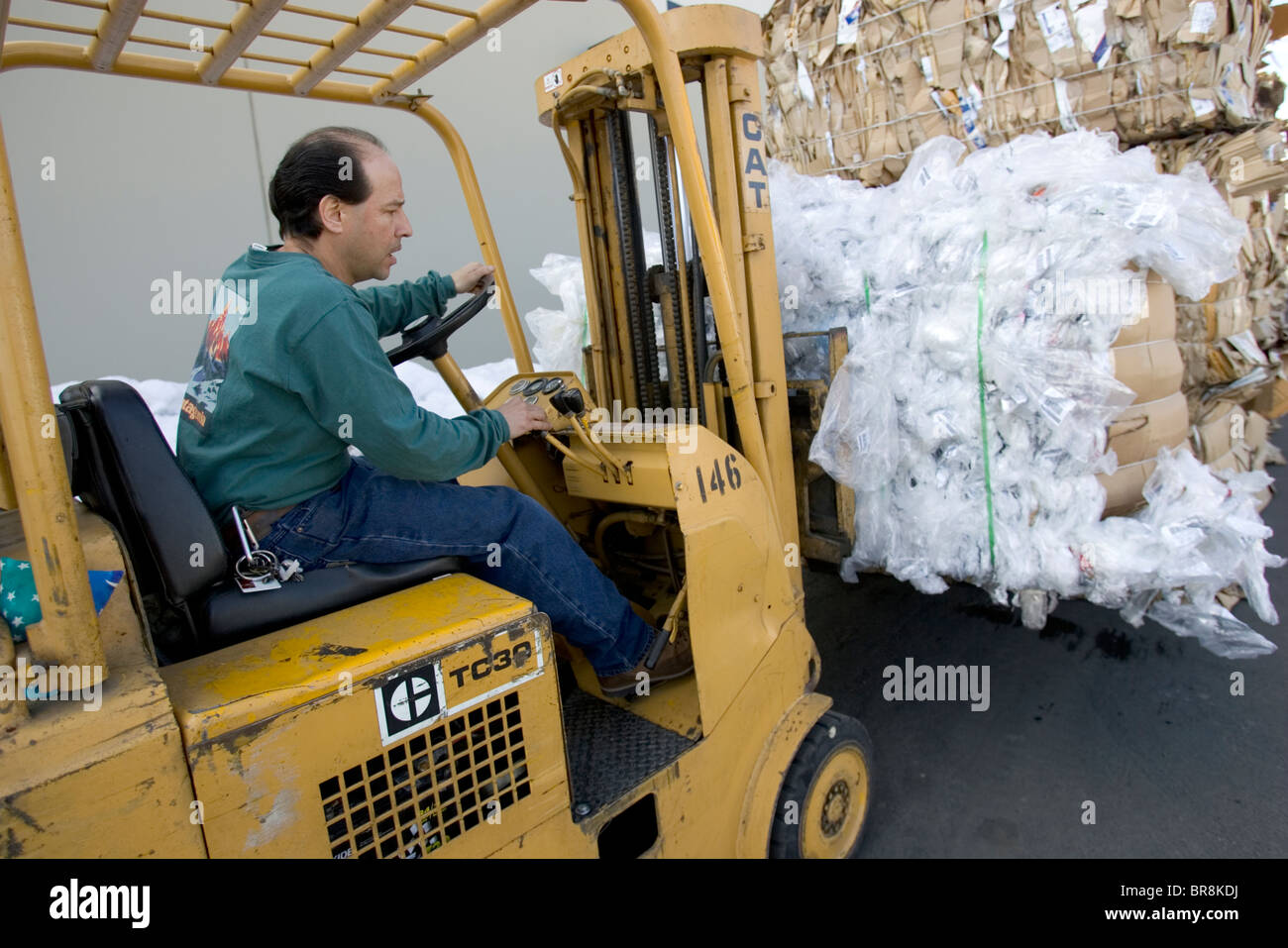 A man moving recycling boxes with a forklift in a clothing distribution ...