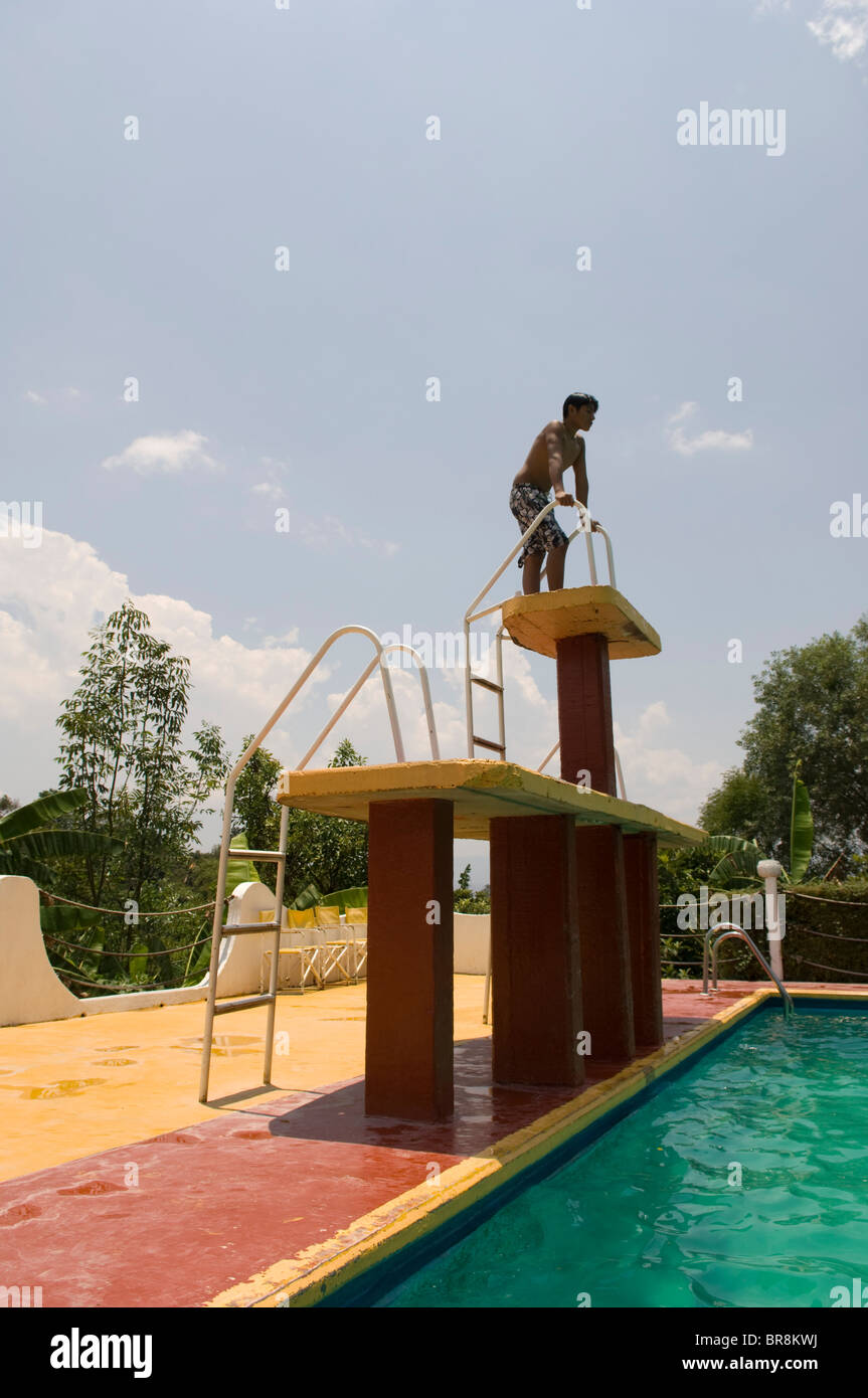 Young man standing on diving platform ready to jump into pool in Oaxaca ...