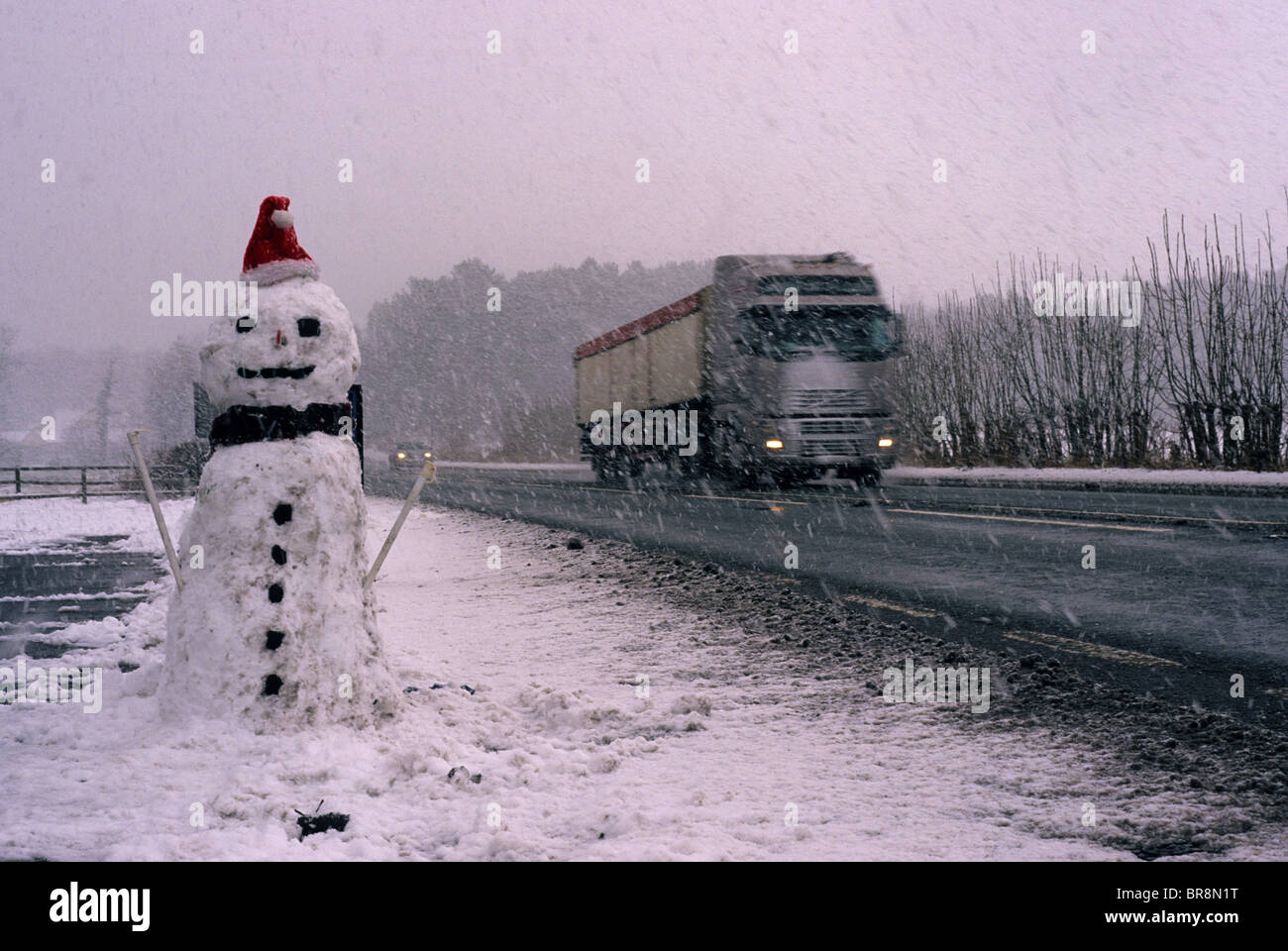 lorry passing roadside snowman on A64 near York in heavy winter snow UK ...