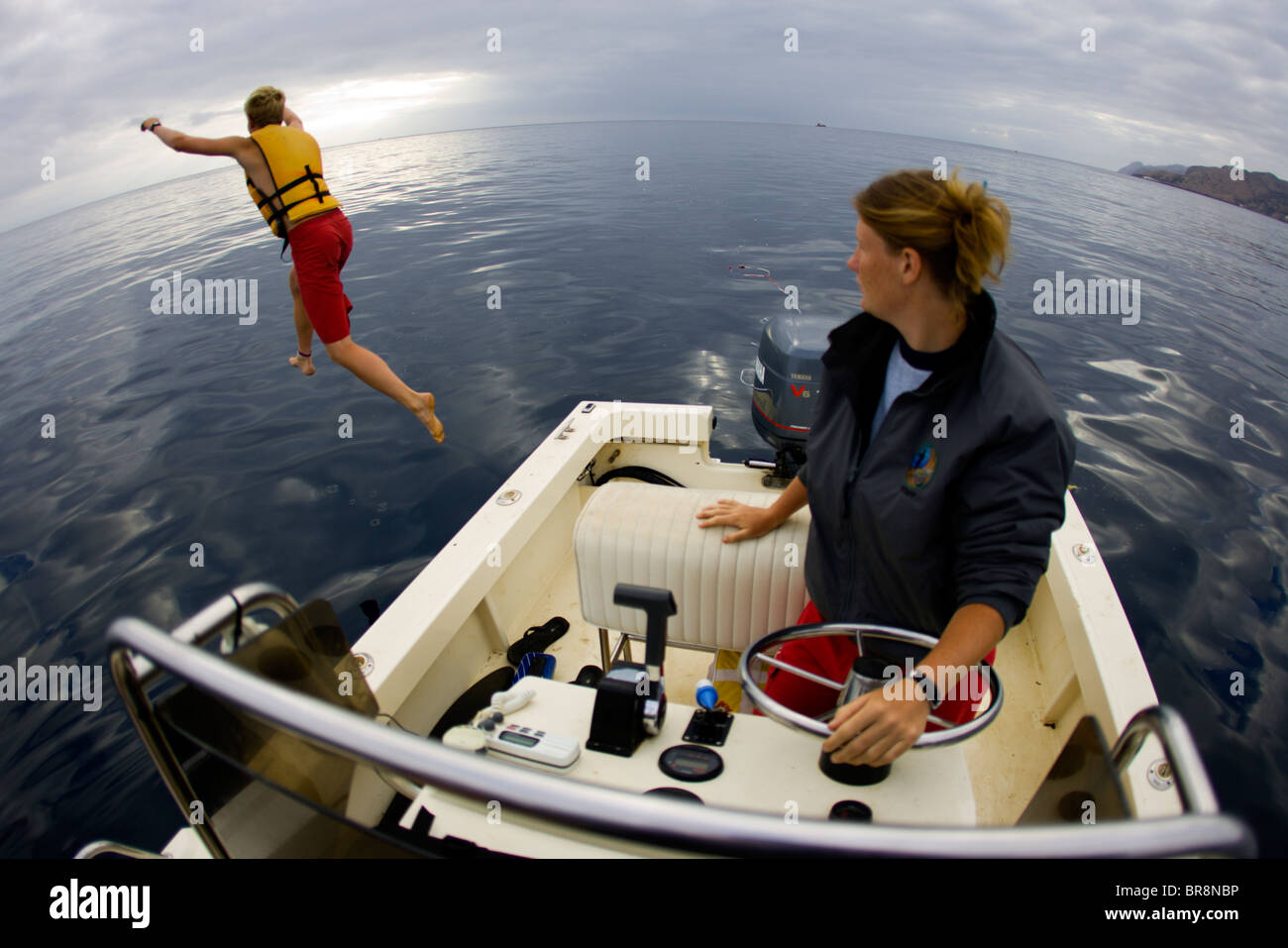 Boy jumping off of a boat into the ocean Stock Photo - Alamy