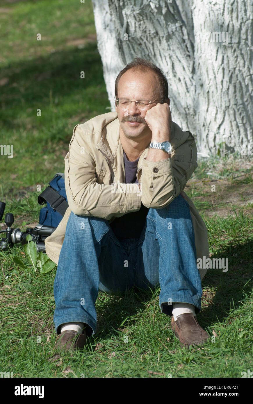 Tired photographer sitting on the grass Stock Photo - Alamy
