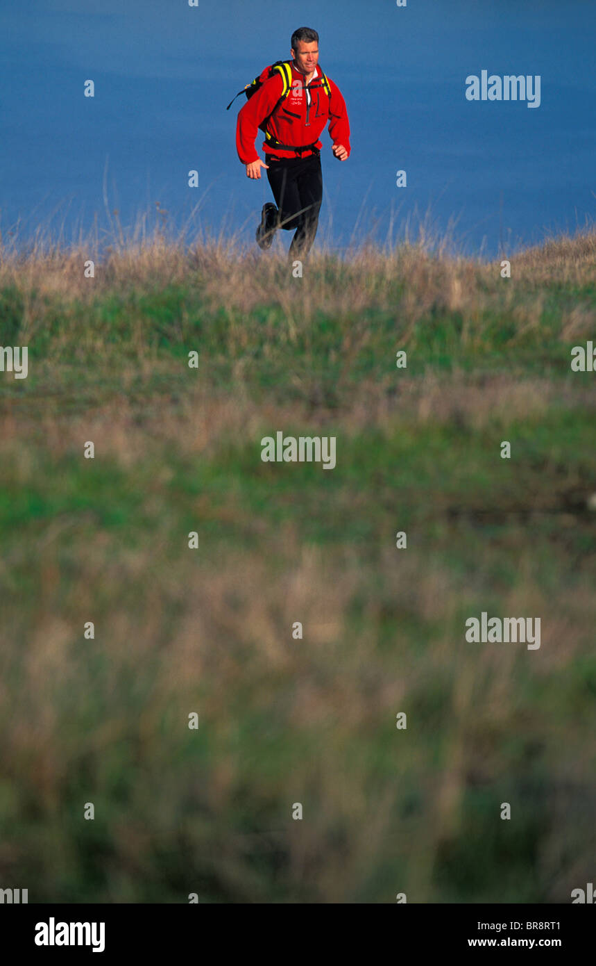 Man trail running in green hills above the ocean Stock Photo - Alamy