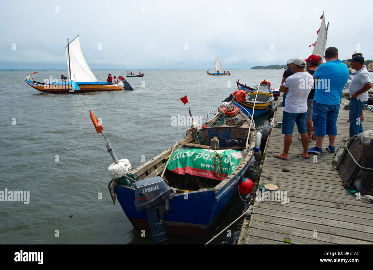 Locals watch from the pier as a traditional Moliceiro boat sets sail ...