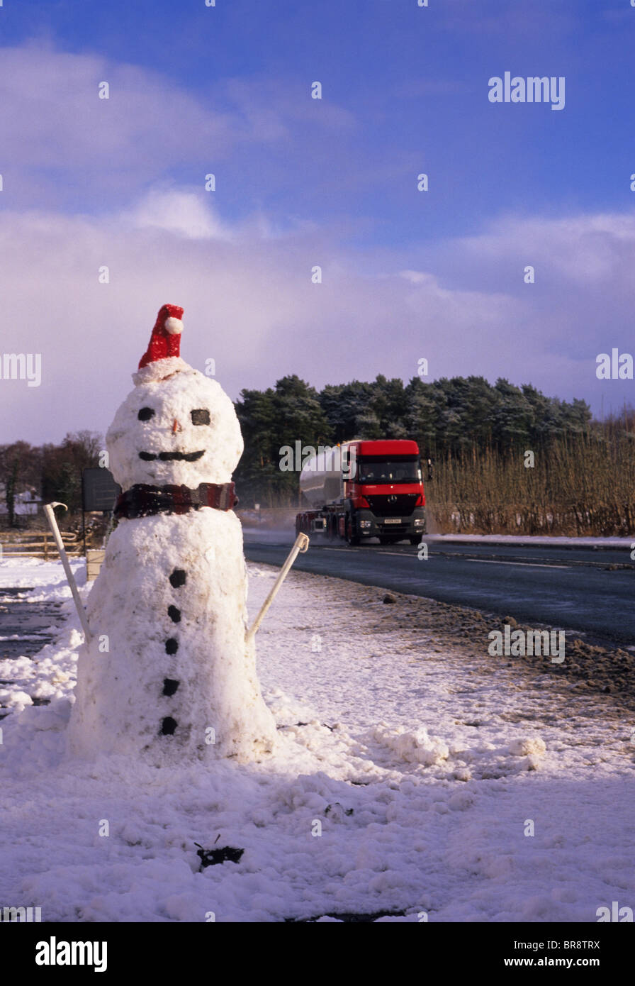 lorry passing roadside snowman on A64 near York in heavy winter snow UK ...