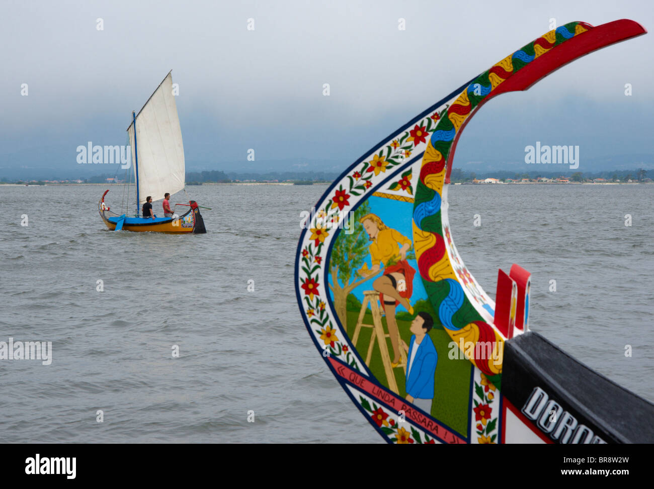 Traditional Moliceiro boat sails by a slightly out-of-focus hand ...