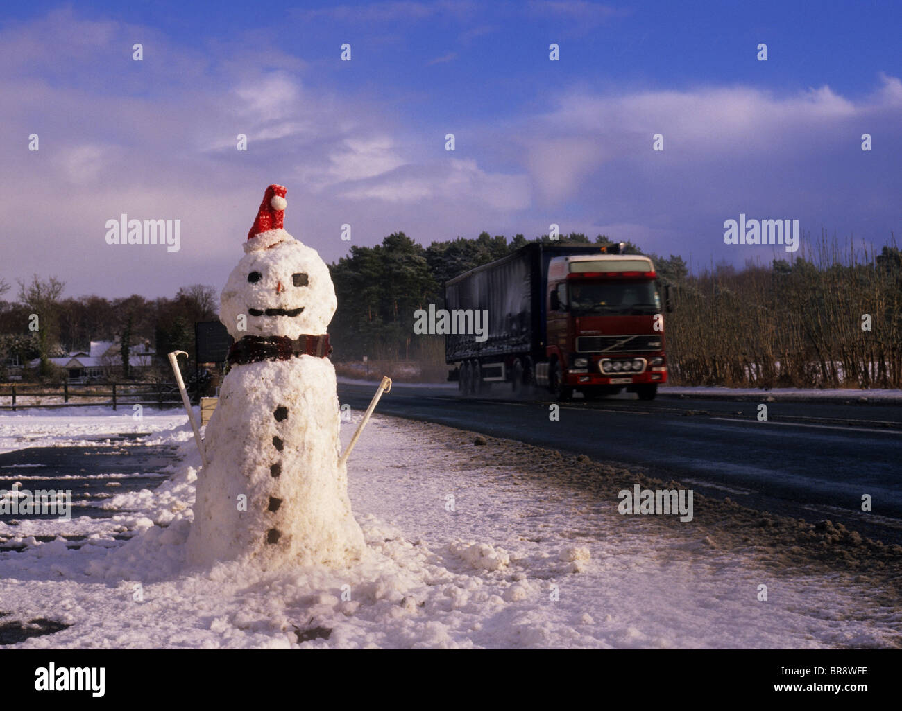lorry passing roadside snowman on A64 near York in heavy winter snow UK ...