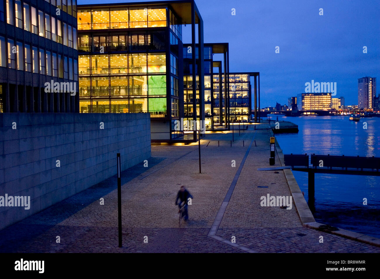 A person cycles past a modern bank building in Copenhagen Denmark Stock ...