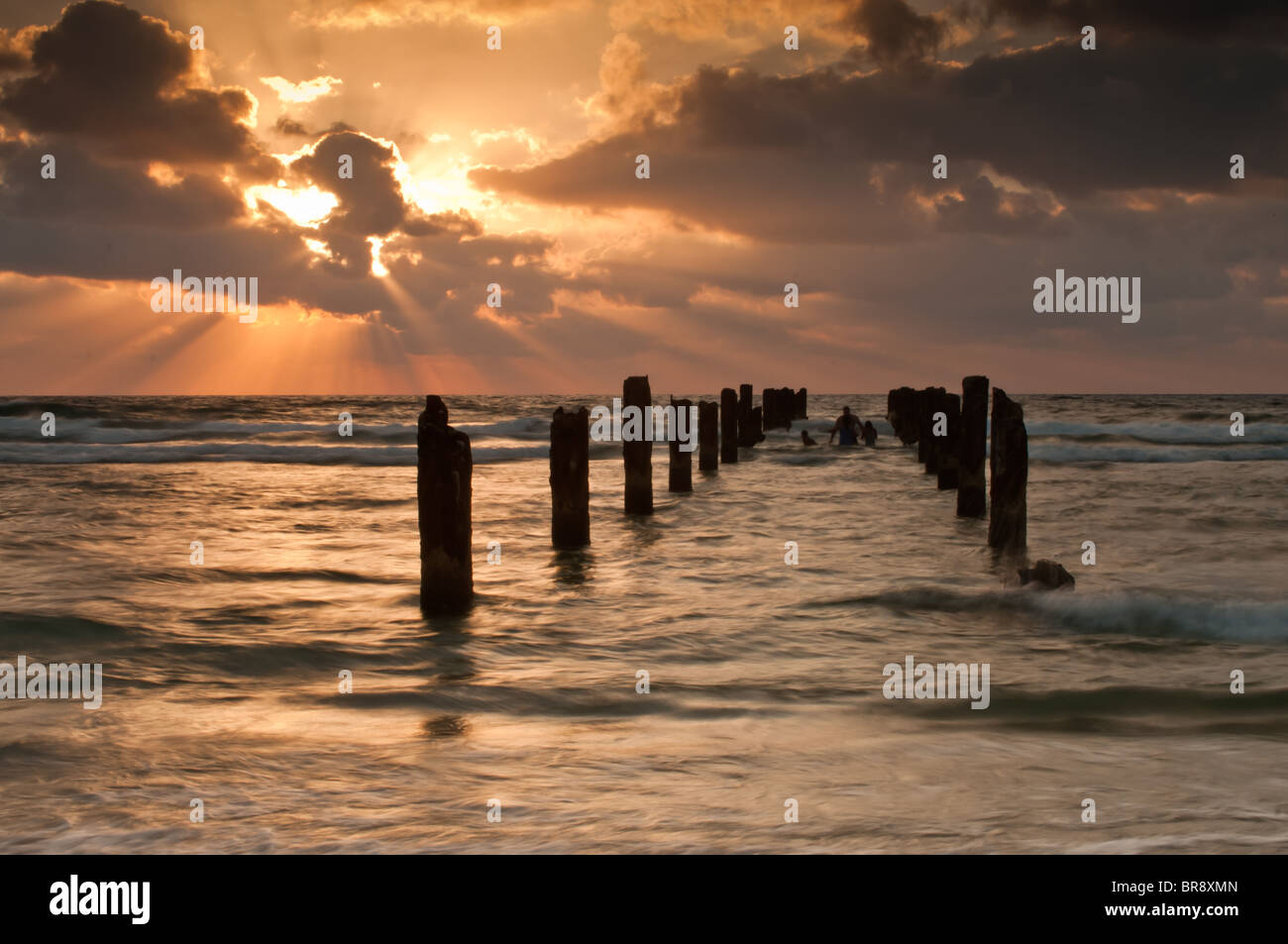 Israel, Beit Yanai, Poles in the sea the remains of a wharf at sunset ...