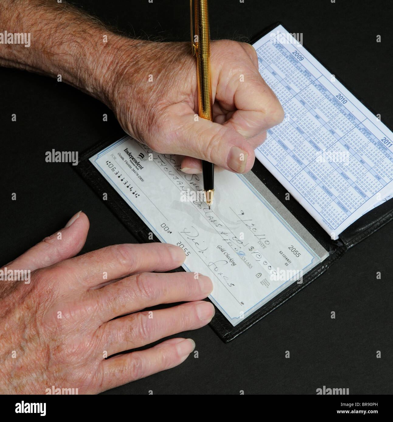 Elderly mans hands writing a Ten Thousand Dollar cheque from ...