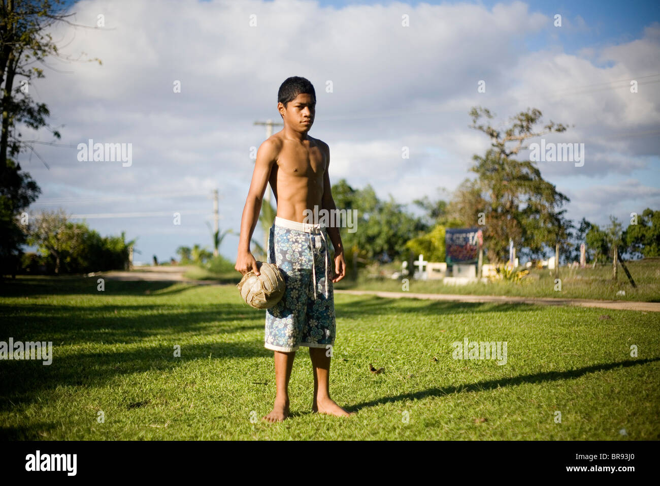 An adolescent boy stands with a beat up ball in hand at dusk Stock ...