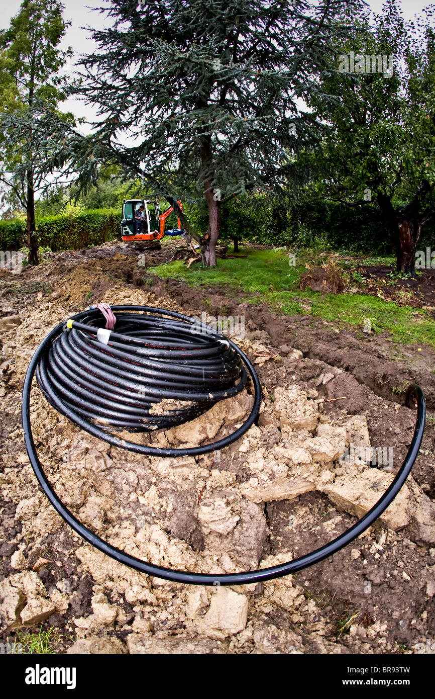 Pipes for geothermal heating system being dug by a mechanical digger ...