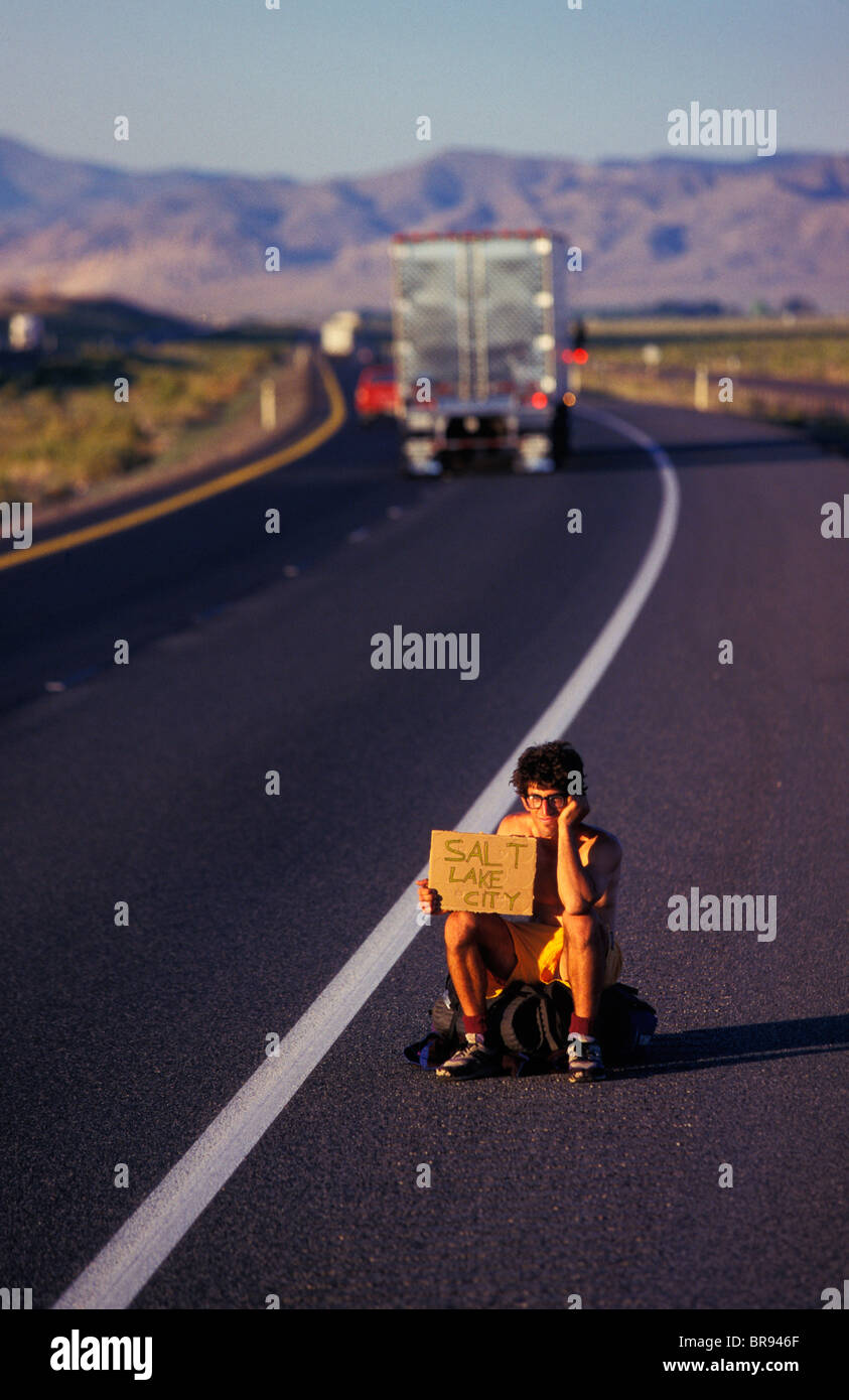 Man with a cardboard sign hitchhiking on a highway at sunset Stock ...