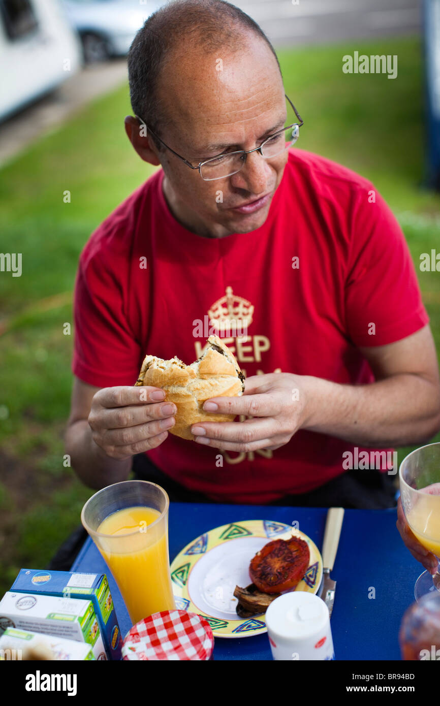 A man eating breakfast outside his motorhome in a caravan park, Poole ...