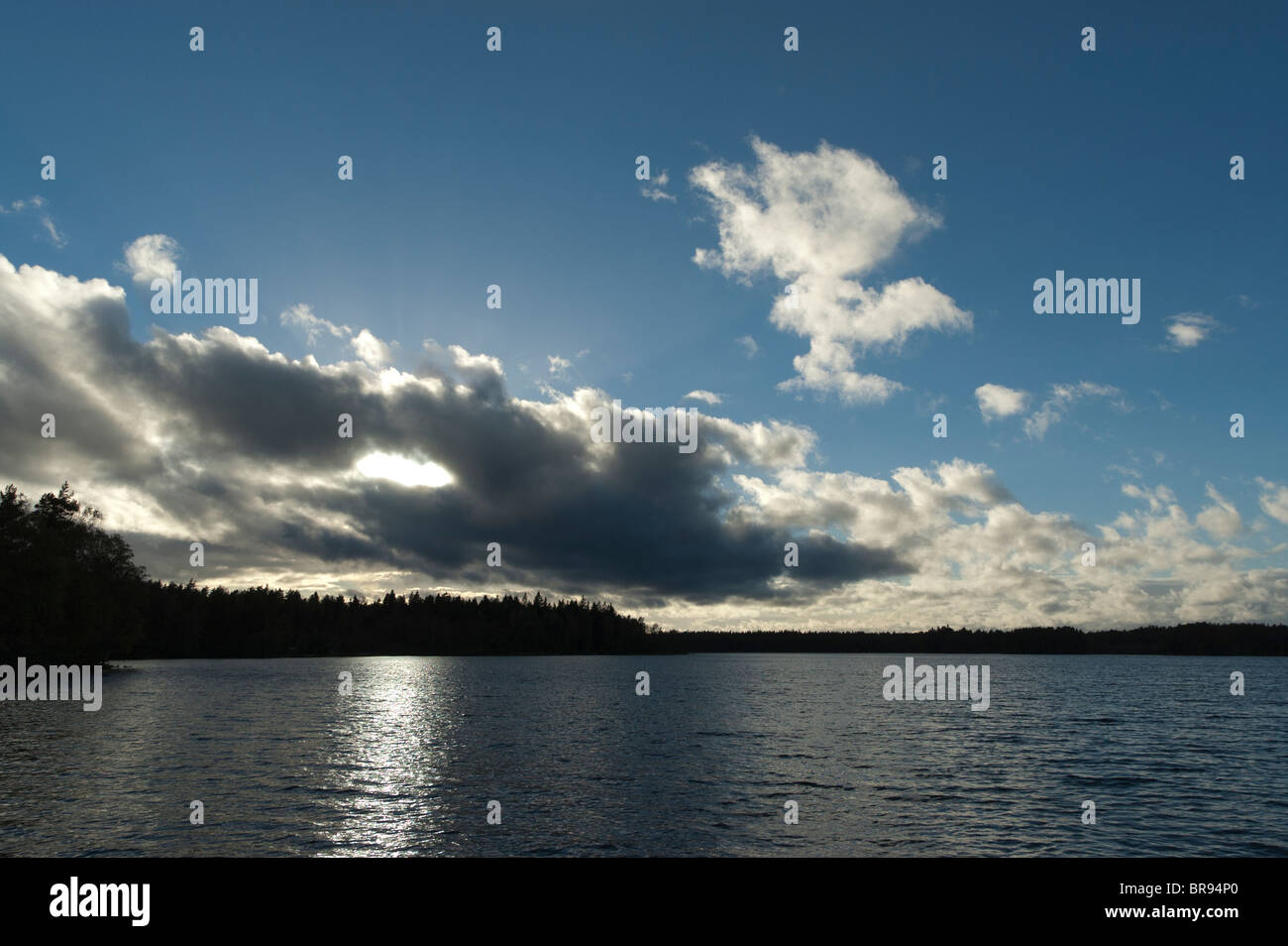 sun breaking through clouds reflecting off lake in Sweden Stock Photo ...