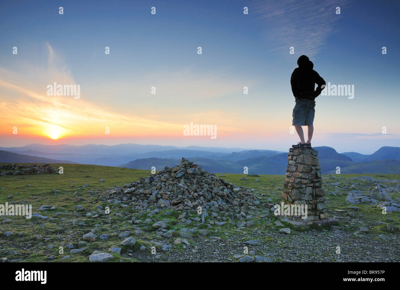 Walker on Pillar summit cairn at sunrise, English Lake District Stock ...