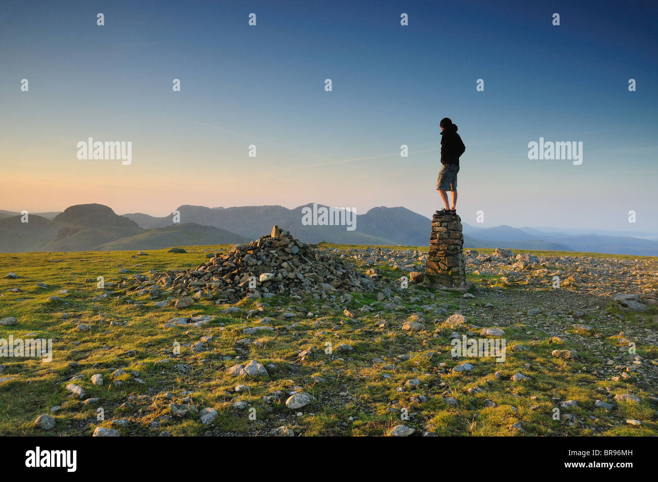 Walker on Pillar summit cairn at sunrise, English Lake District Stock ...