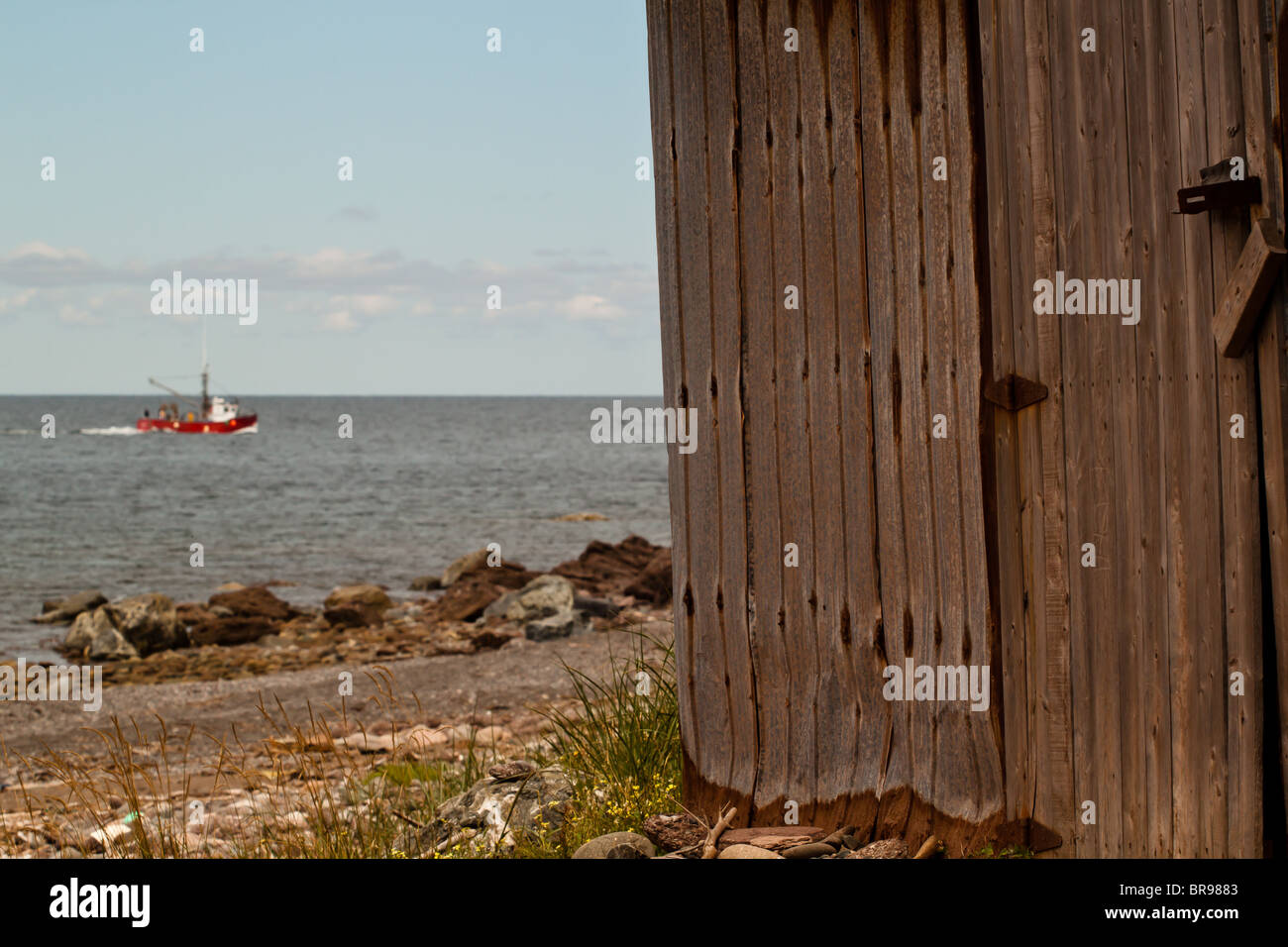A small fishing boat coasts by a wooden shack Stock Photo - Alamy
