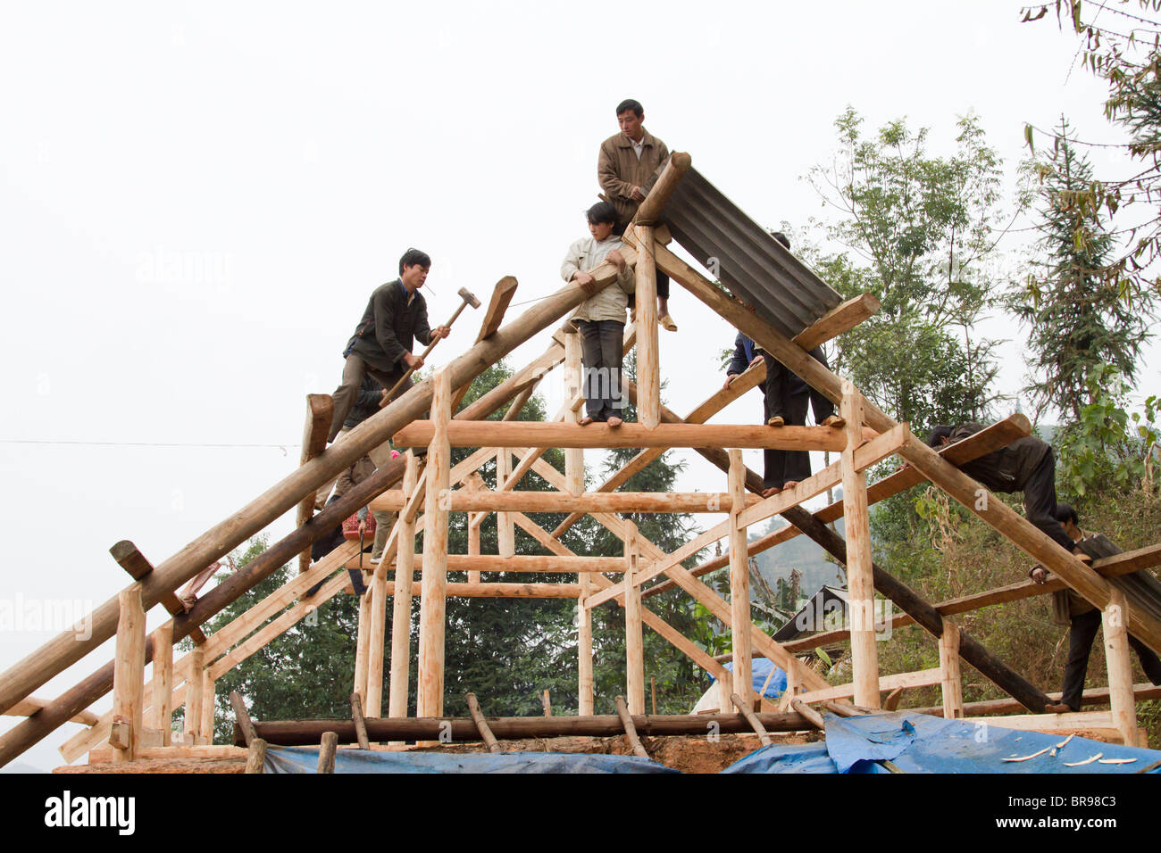 Flower hmong men put asbestos roof tiles on a house near Bac ha ...