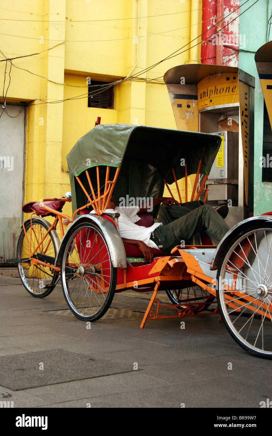 Rickshaw driver resting in George Town, Penang Island, Malaysia Stock ...