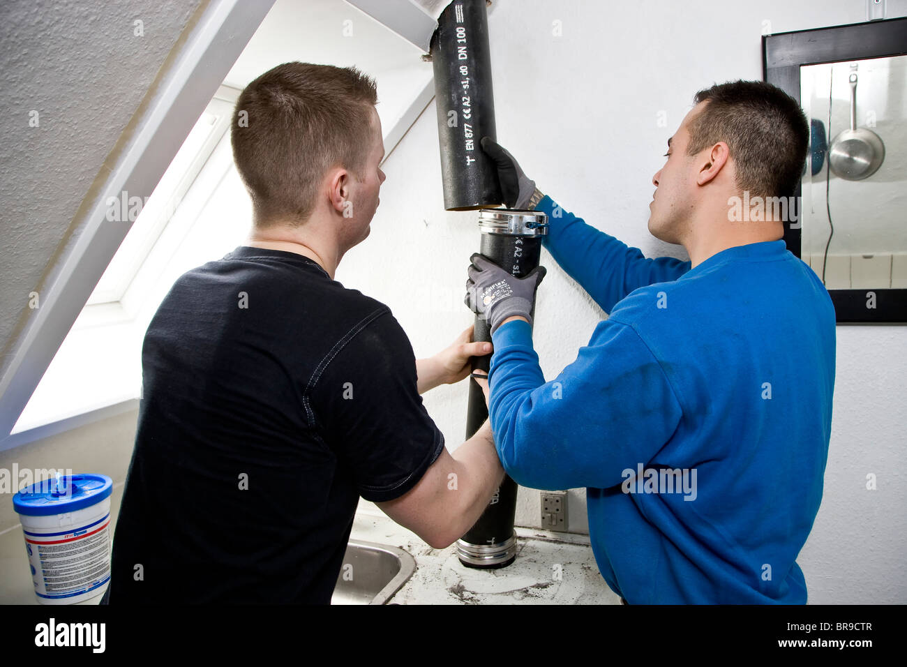 Two plumbers replace old leaky drainpipes with new pipes Stock Photo ...